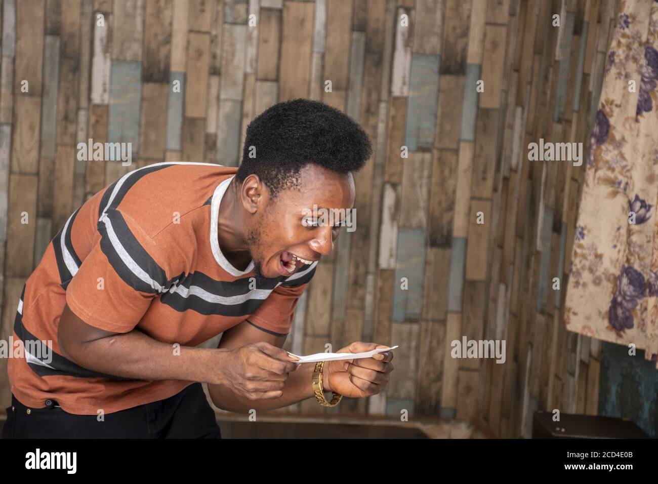 Young African male feeling excited and happy while holding a paper slip ...