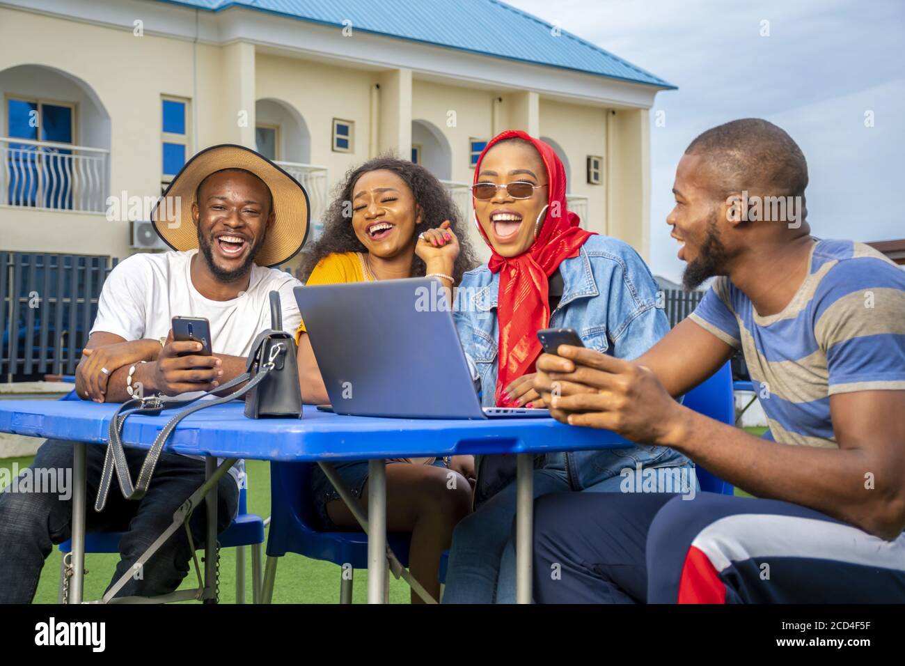 Group of cheerful friends communicating and using devices Stock Photo ...