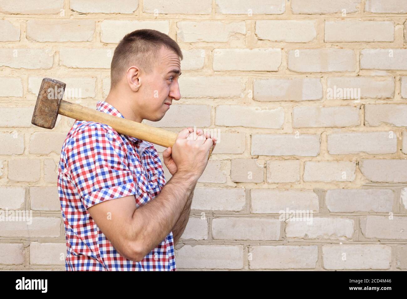 Man with a hammer on the shoulder, on the brick wall background ...