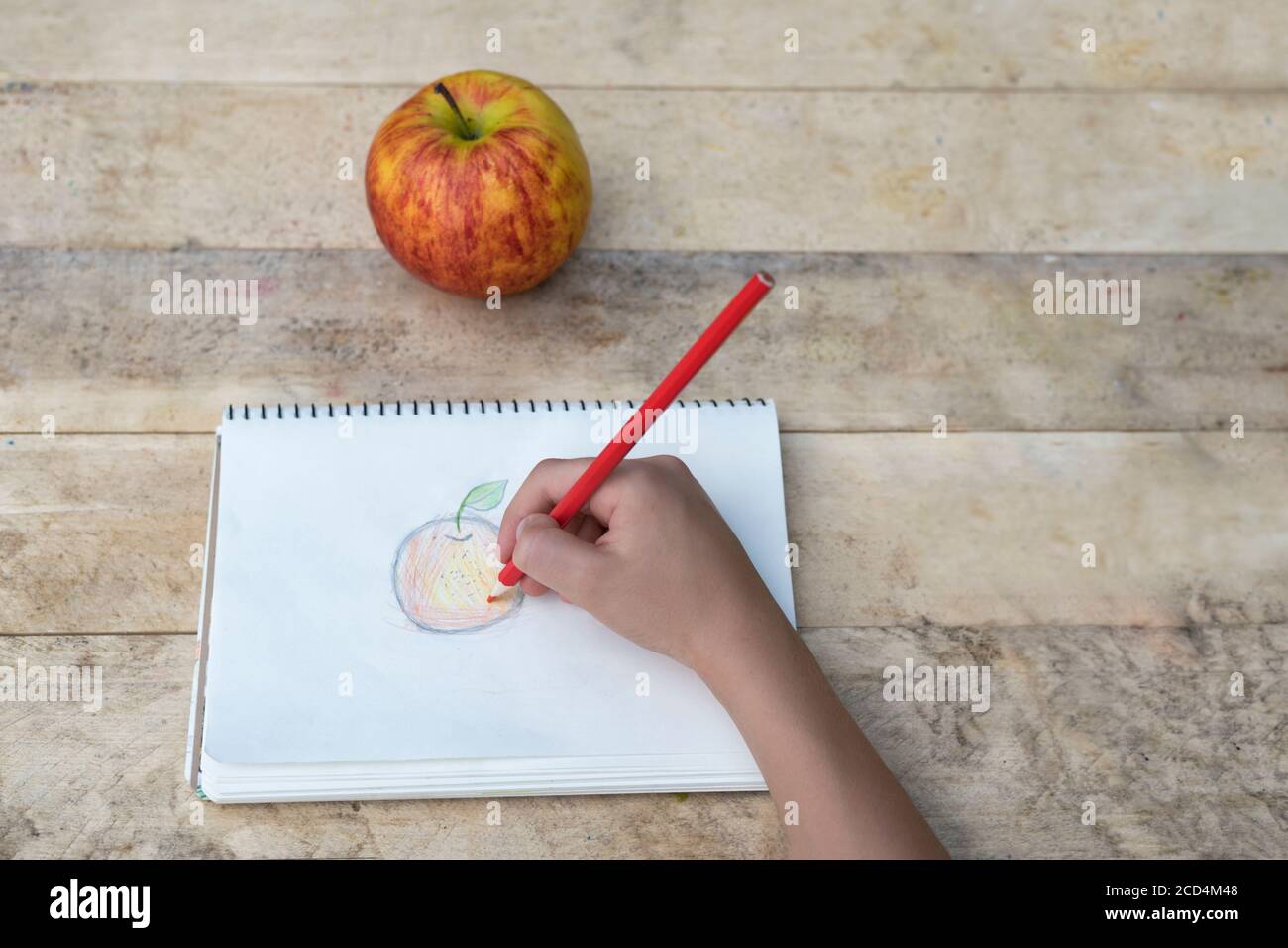 Children's hands draw an apple with colored pencils. Top view Stock ...