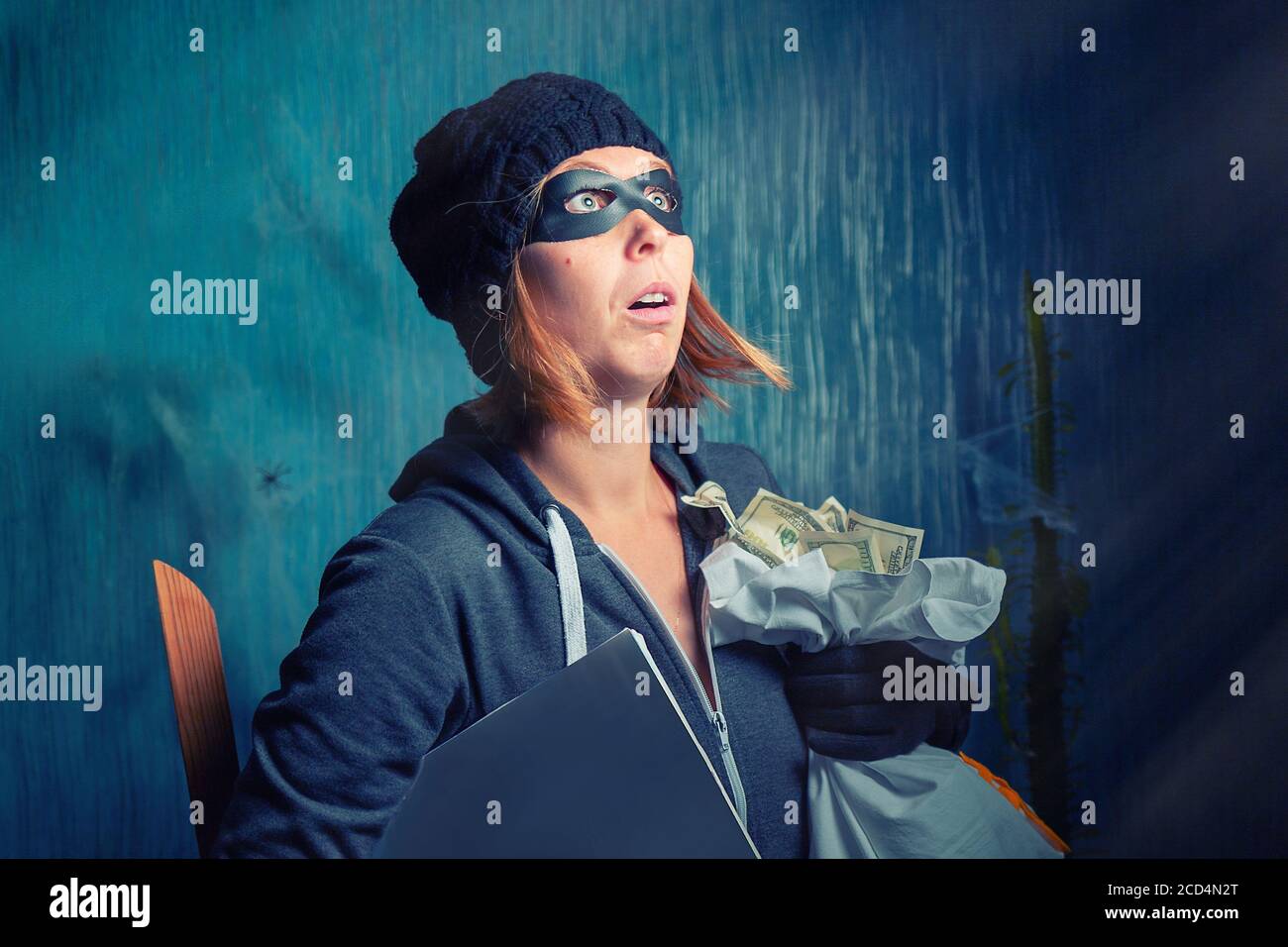 Portrait of a woman robber in a mask, with a stolen bag of money in her ...
