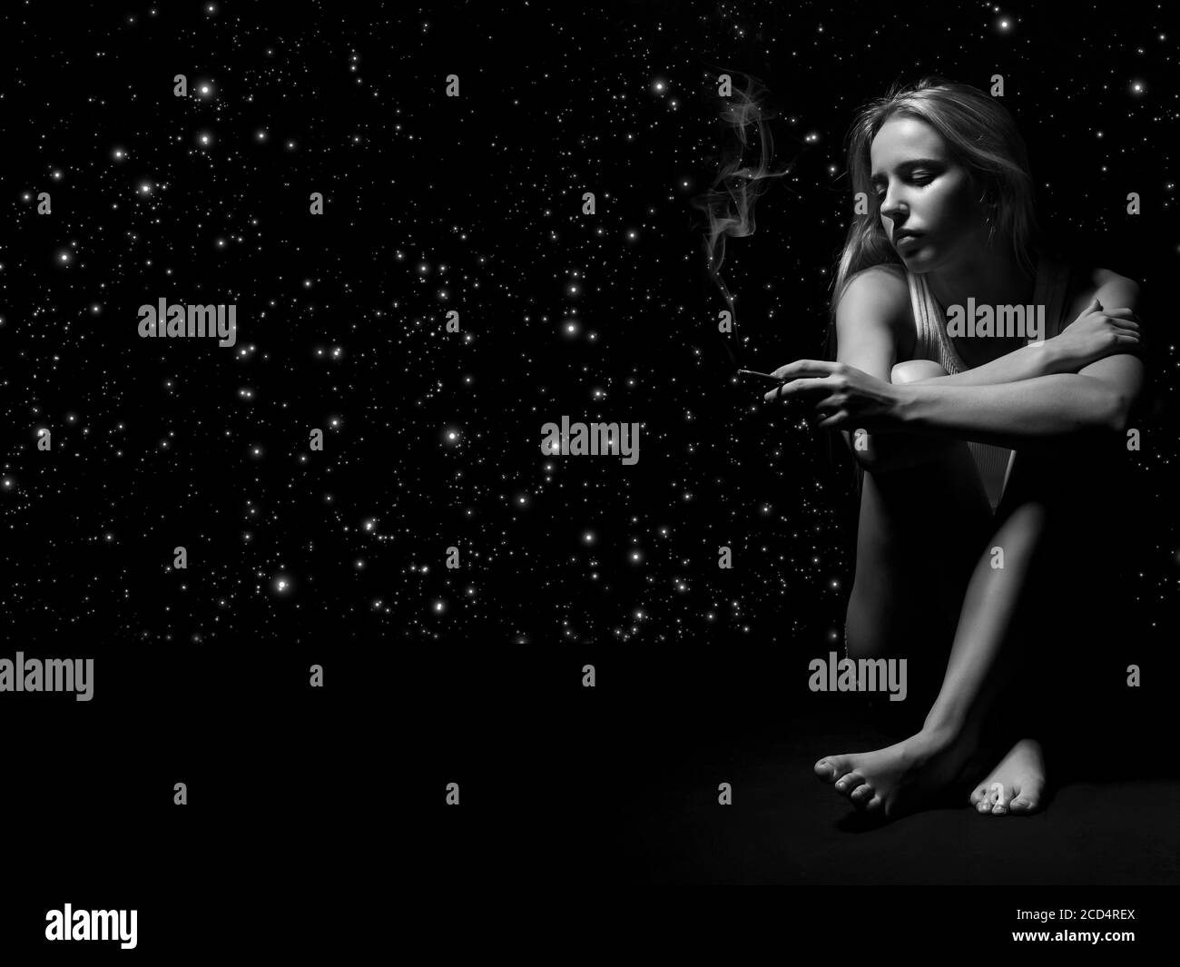 young sad woman sitting in dark, smoking cigarette on stars background ...