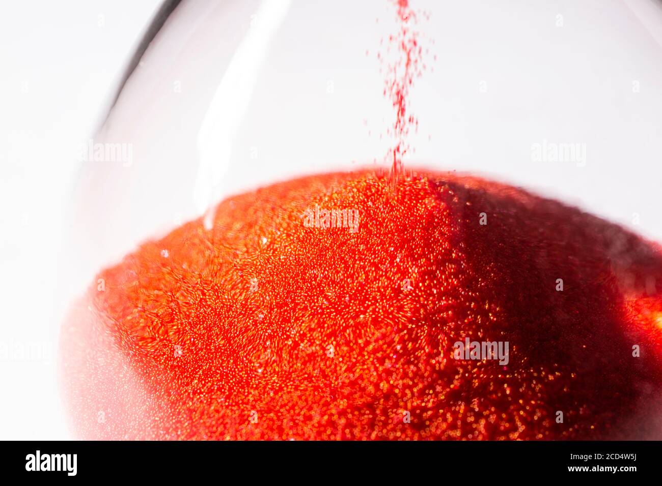 hourglass with red sand used to measure time flow, macro photography ...