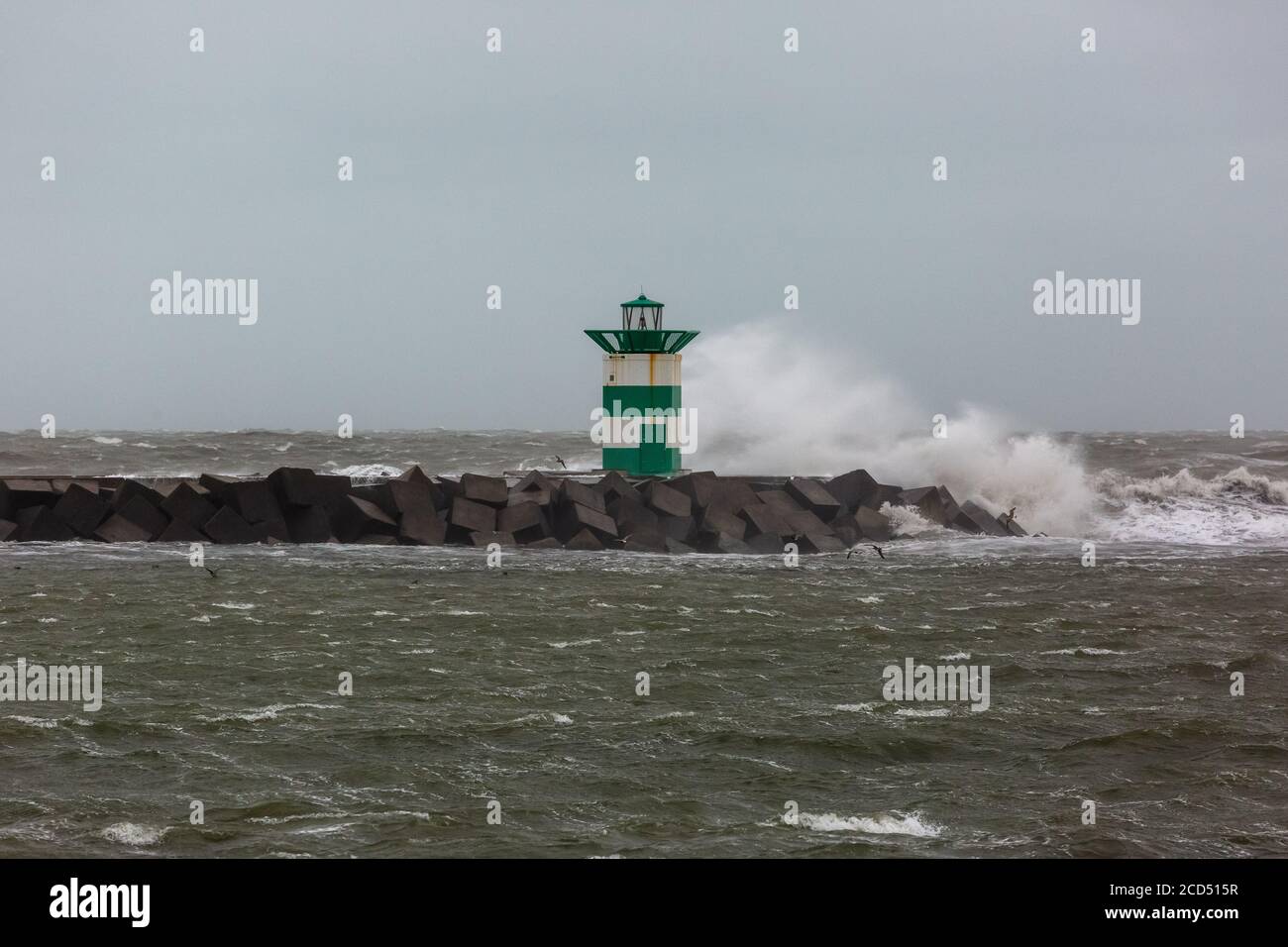 Harbor lights at the end of a dam during a storm with swishing water ...