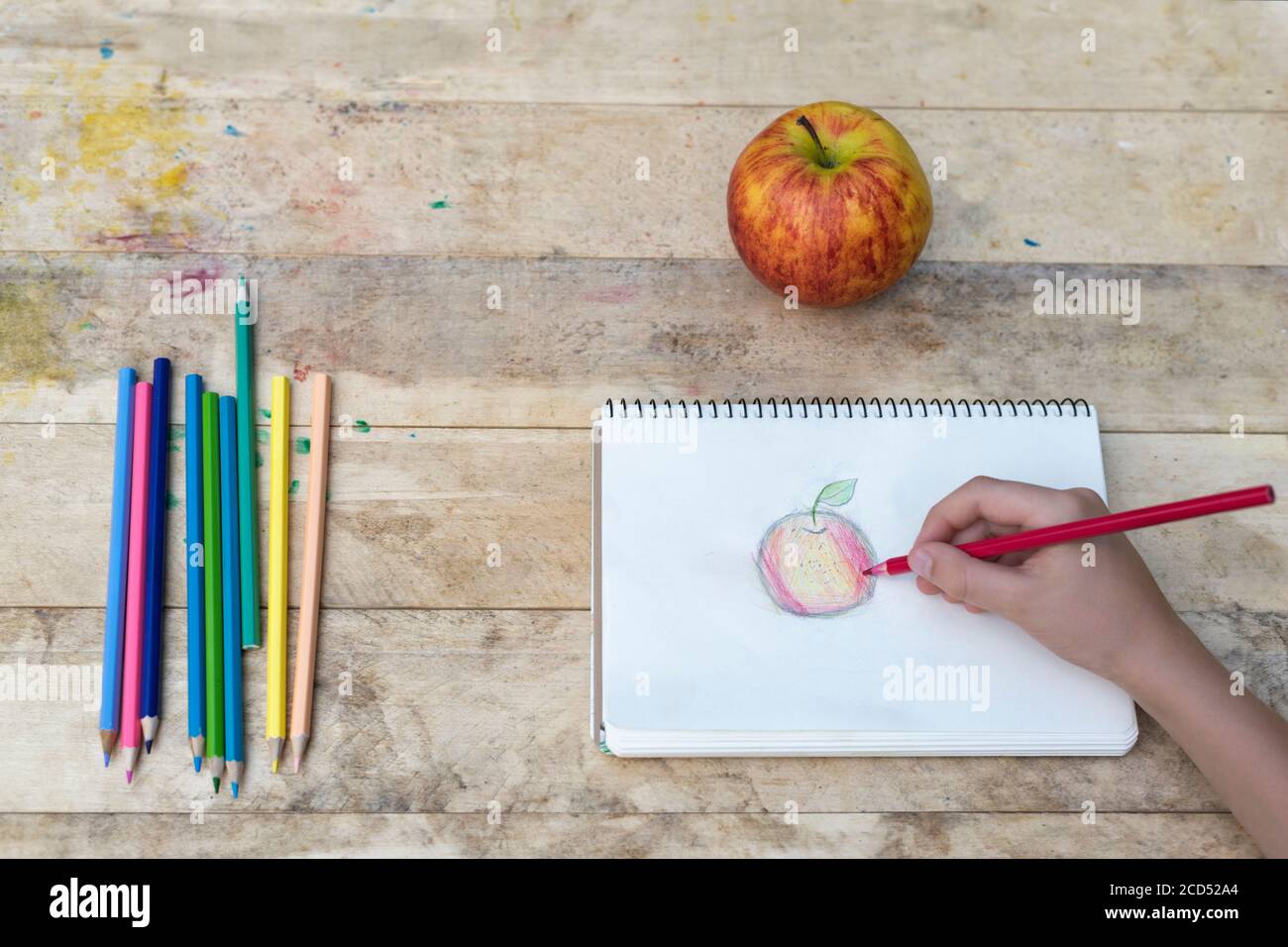 Children's hands draw an apple with colored pencils. Top view Stock ...