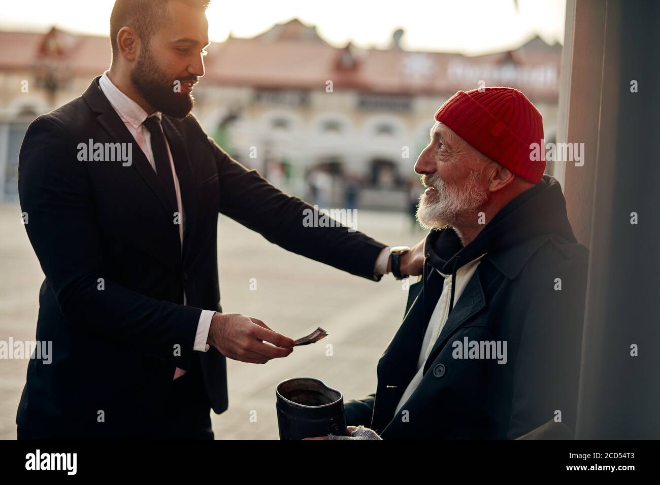 Businessman in tuxedo help to vagrant man sitting on street with rusty ...