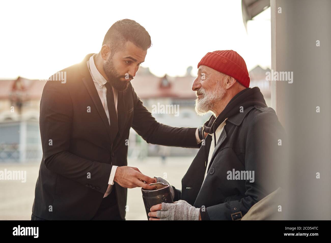 Poor senior man wearing coat, suffering from cold weather meet rich man ...