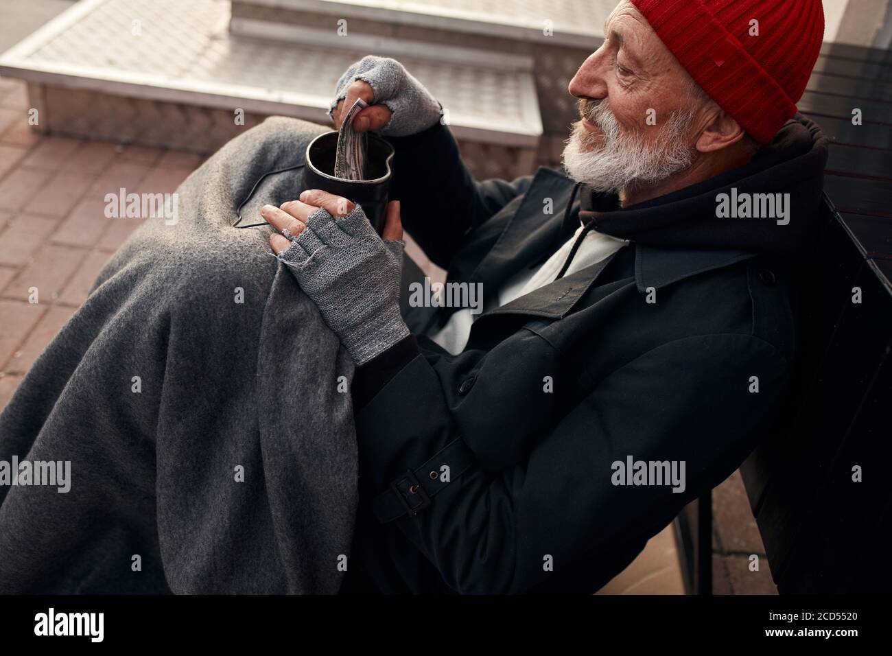 Beggar male sit with jar for money, wearing warm old clothes. Vagrant ...