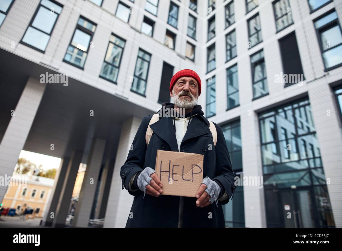 Poor man holding help sign made by cardboard, stand in the center of ...
