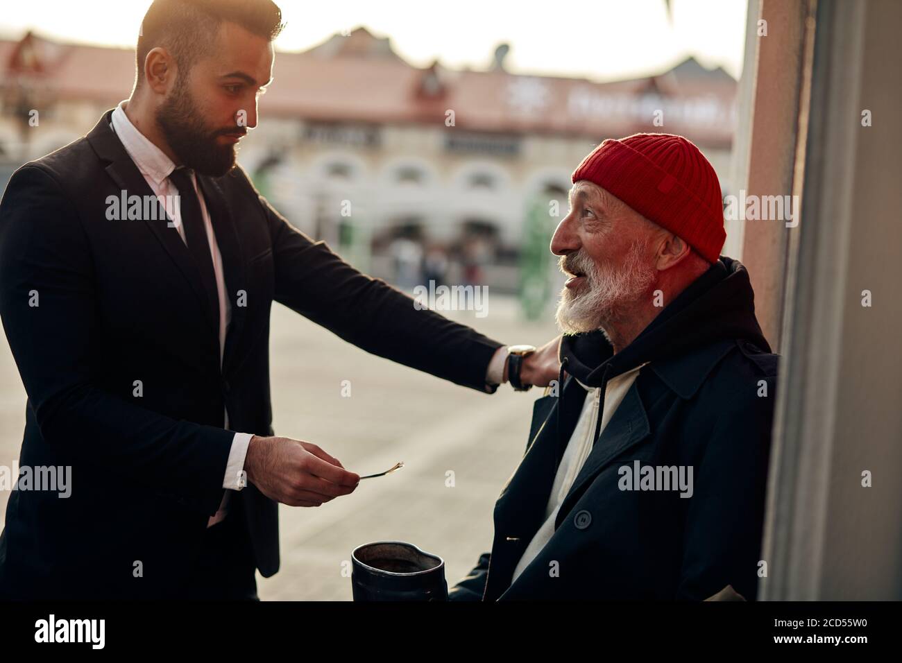 Businessman in tuxedo help to vagrant man sitting on street with rusty ...