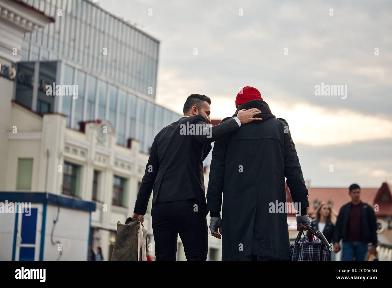 Rear view on rich man decided to help poor man. Young bearded man in ...