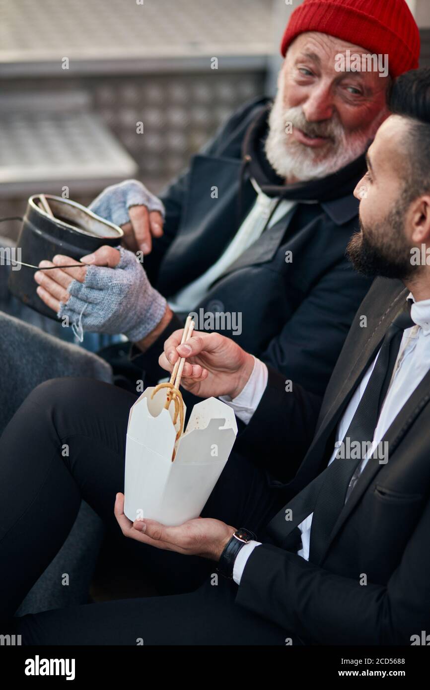 Beggar man with kind eyes, happily look at man. Handsome businessman in ...