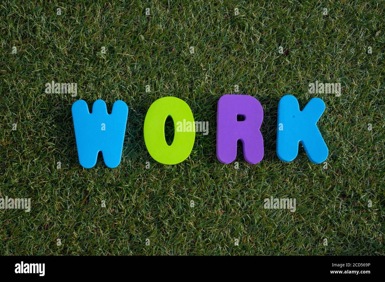Capital letter "Work" word from colorful of wood on grass background ...