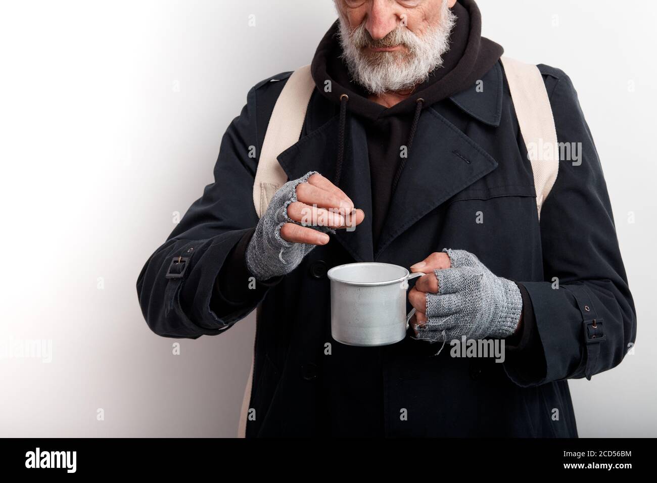 Homeless mature bearded man in black coat and white backpack holding ...