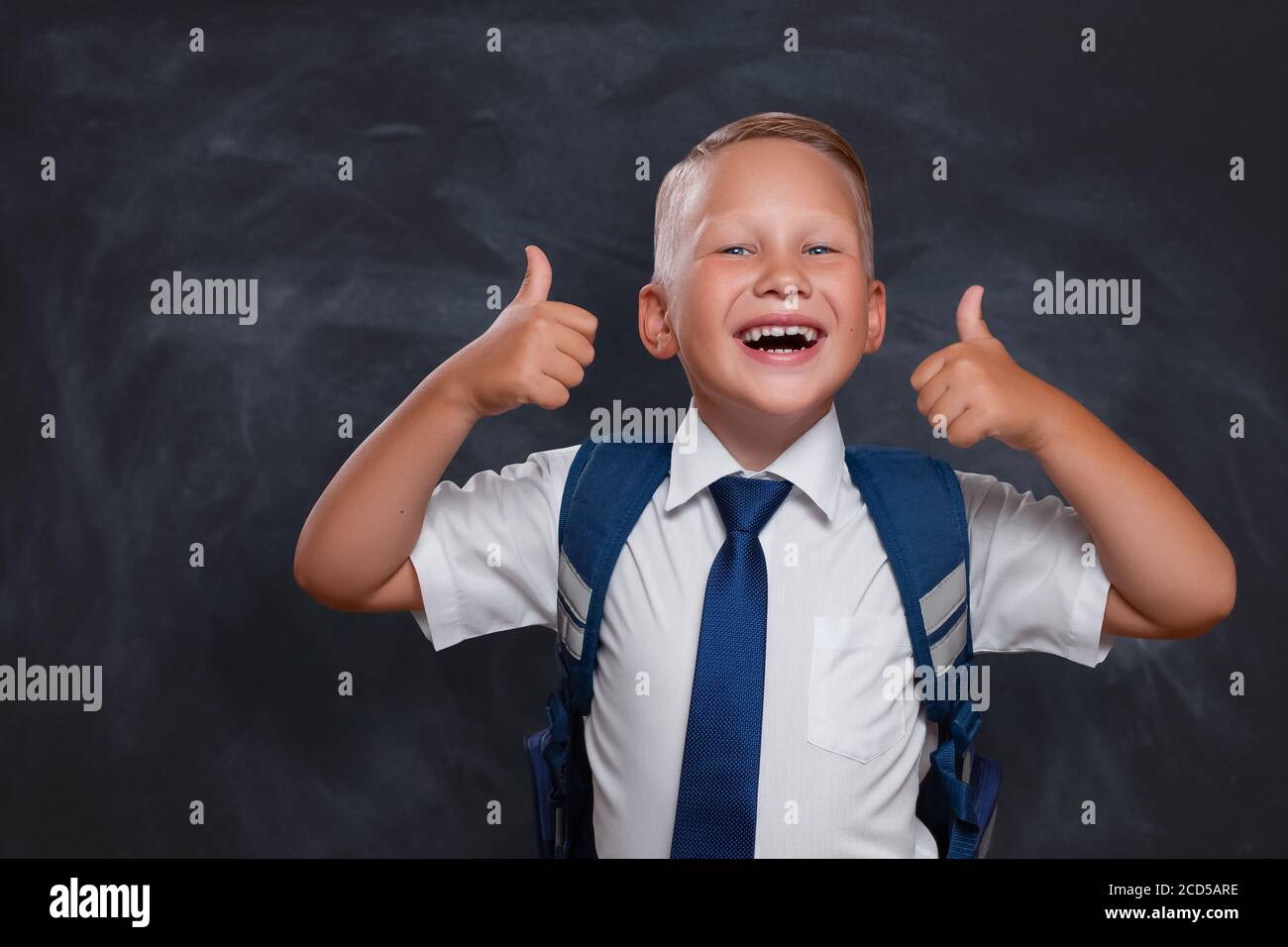Successful elementary school student showing his thumbs up on ...