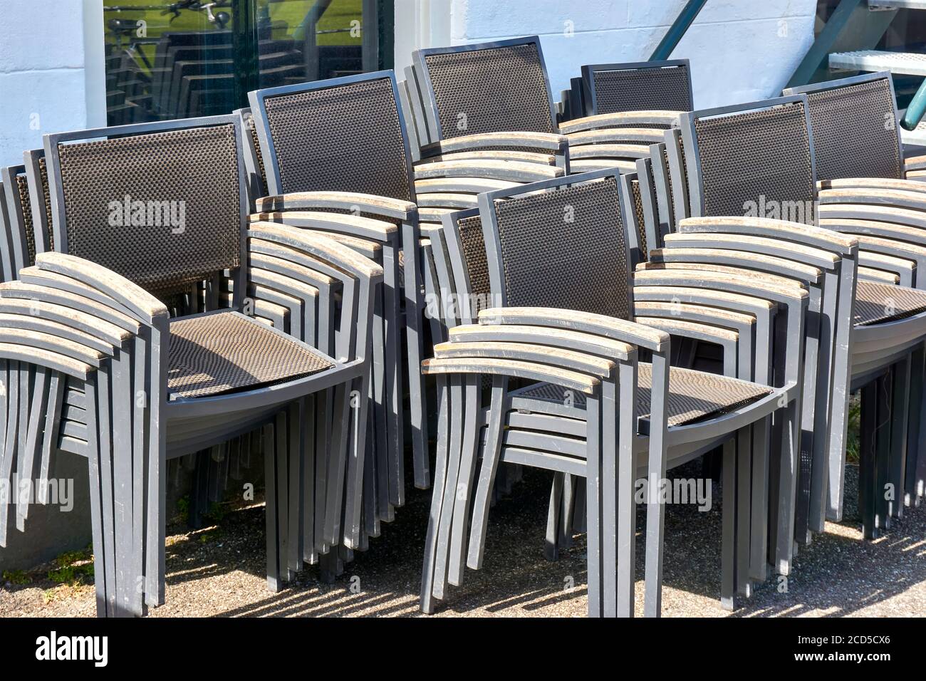 Stacked grey metal chairs with wooden armrests on the terrace of a ...