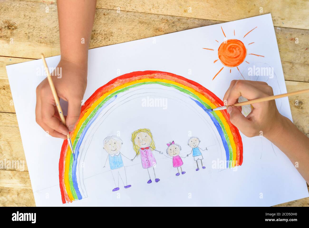 Two children's hands draw a drawing with a brush and paints. Top view ...