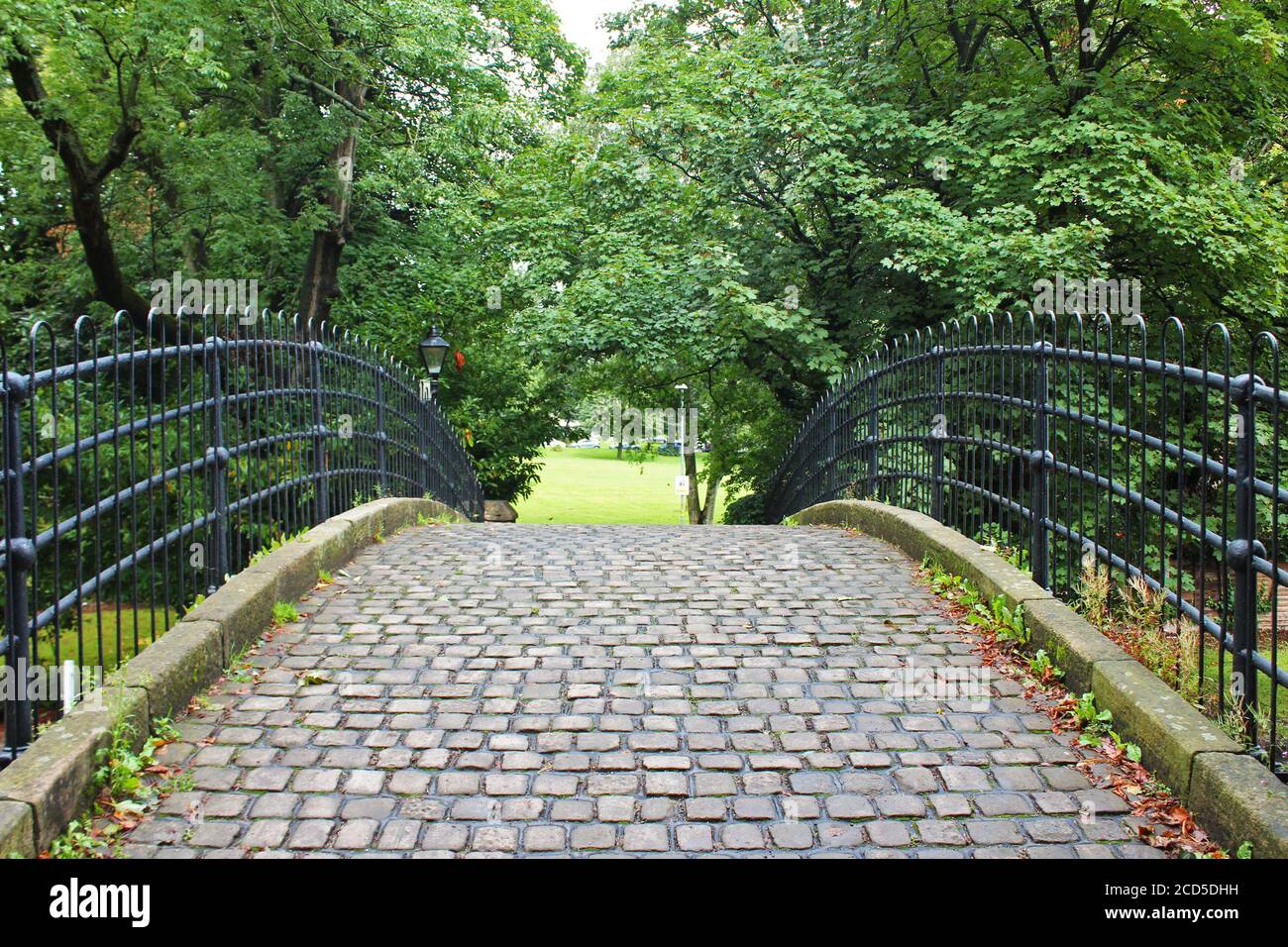 Pretty hump-backed cobblestone bridge with trees in Worsley village ...