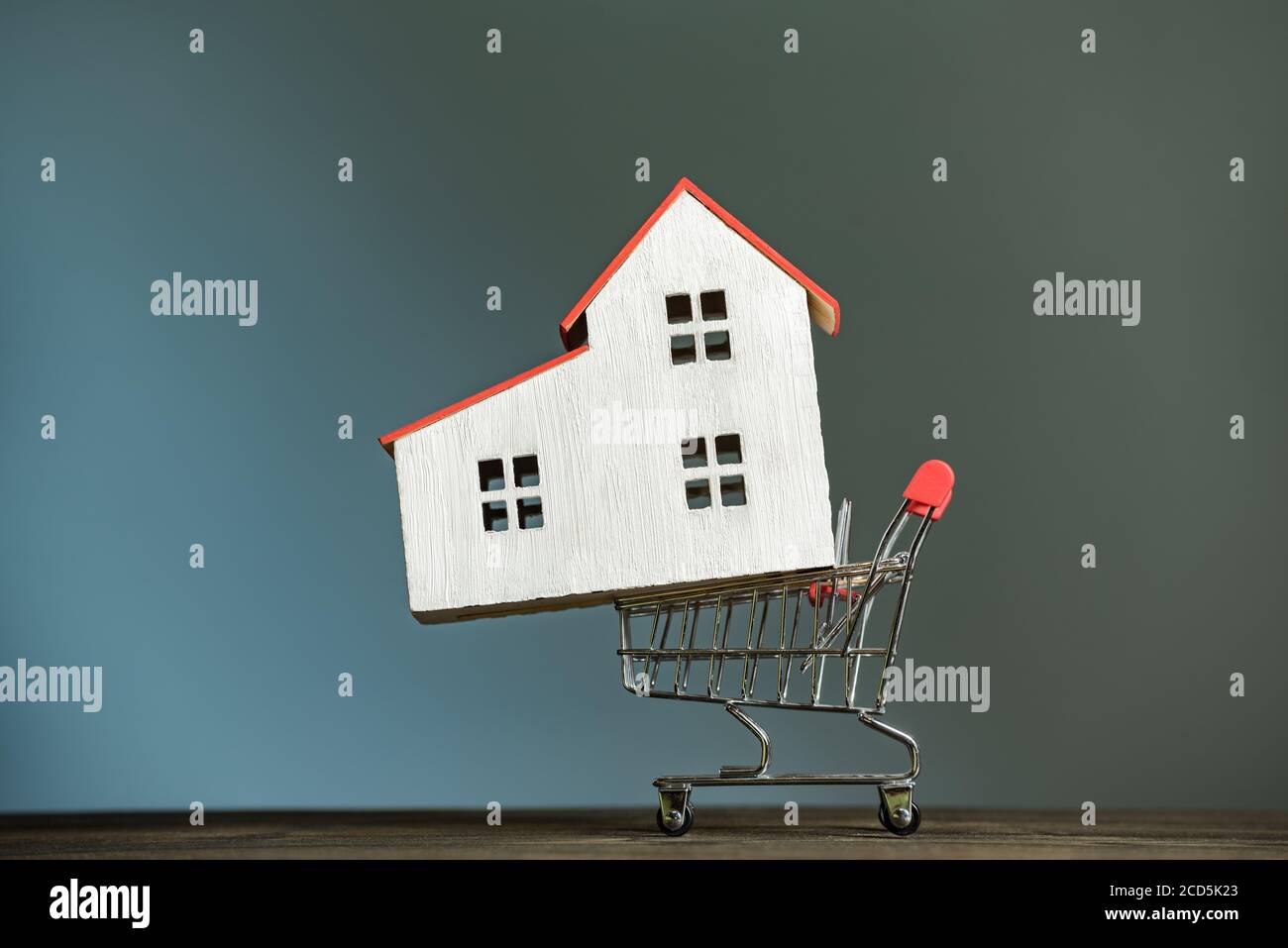 Model home on the shopping cart. Buy house concept. Dark background ...