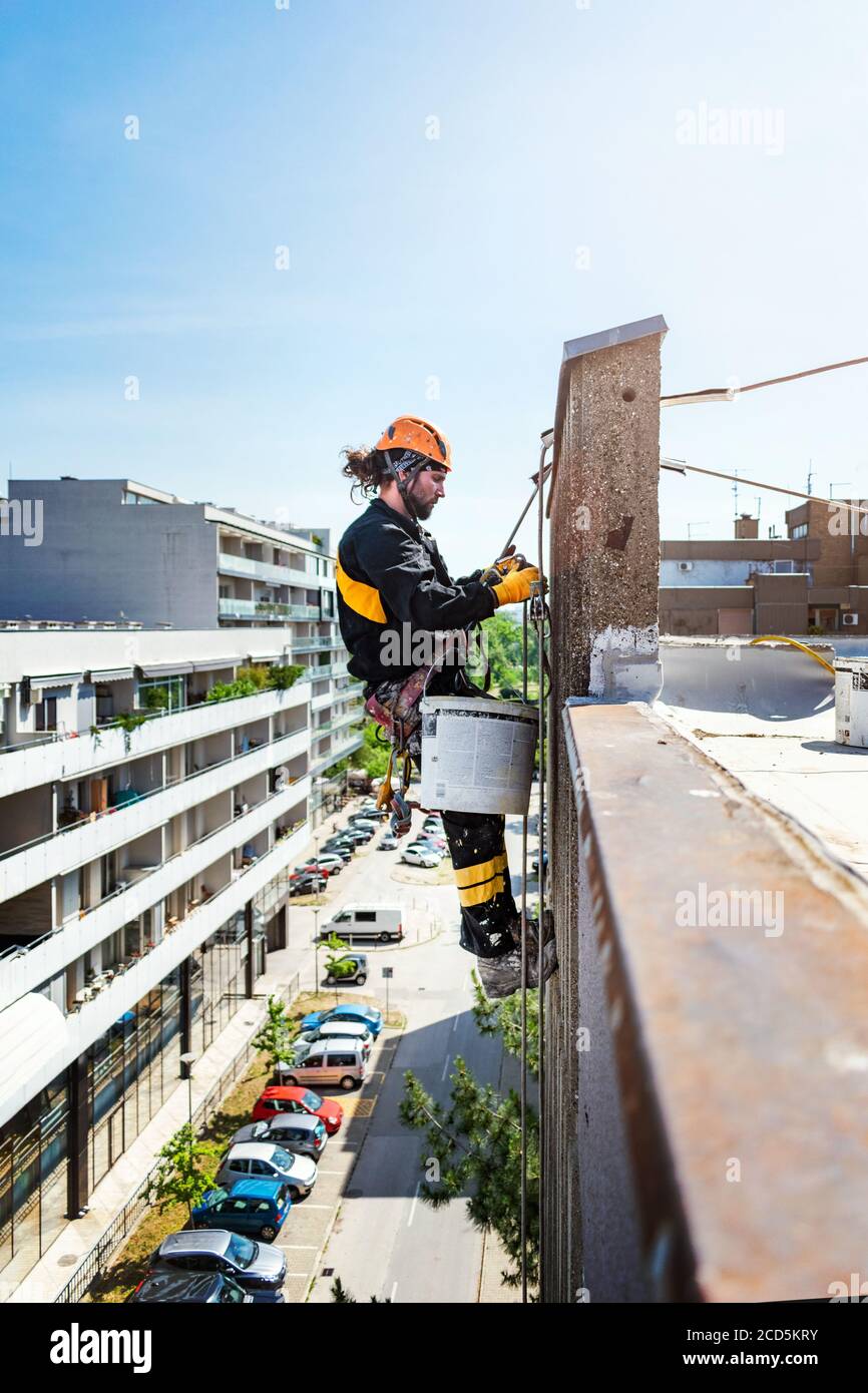 Male worker hanging on rope access and height construction project ...