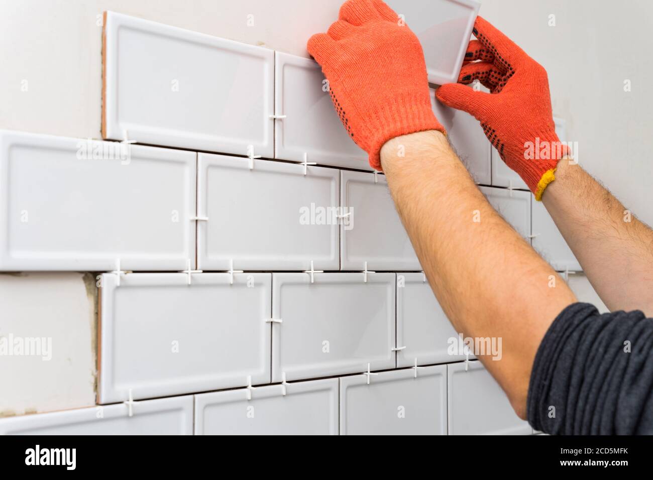 Worker is tiling the white tiles on the kitchen wall. Concept of a ...