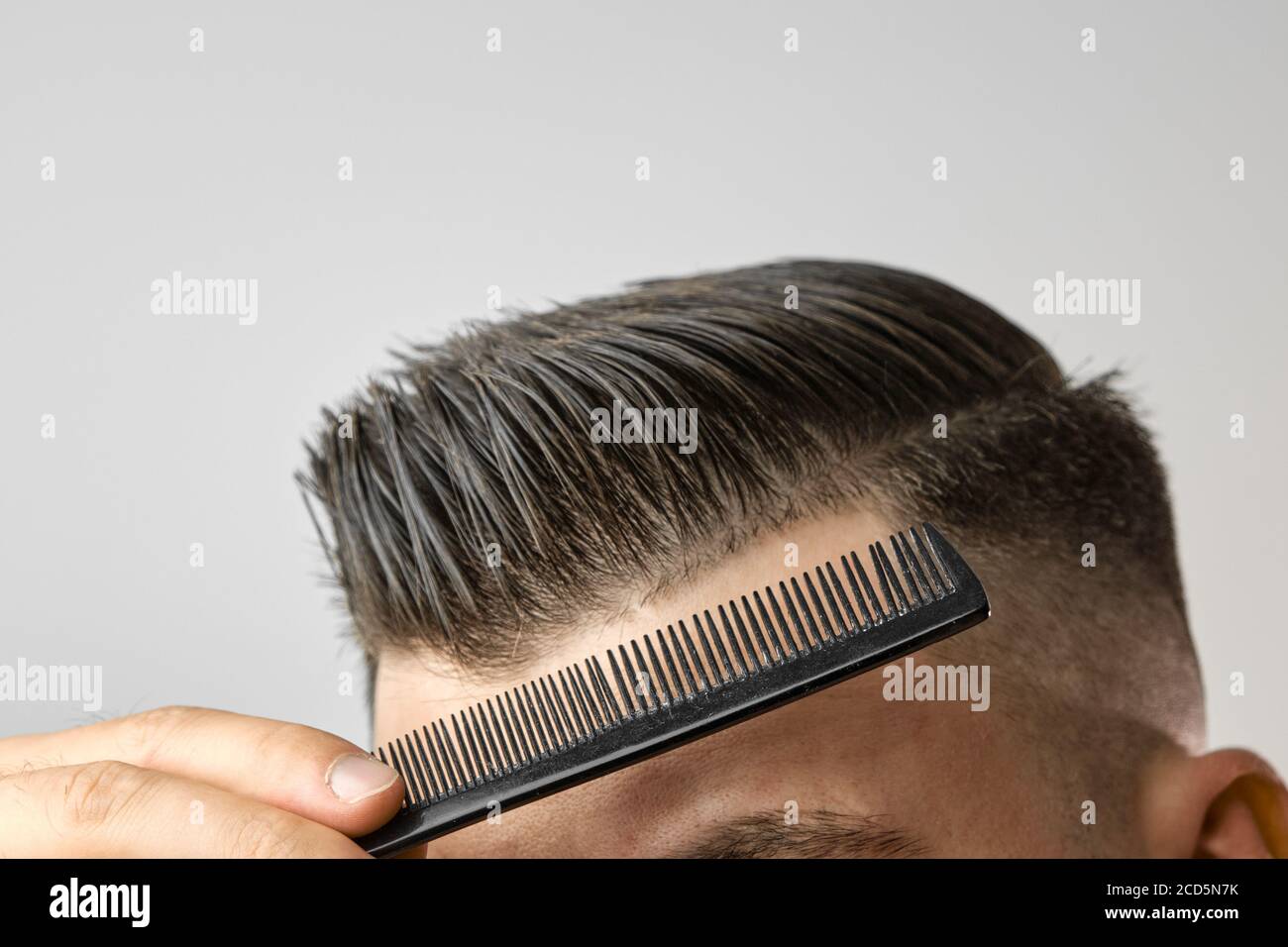 Close up young man combing his hair with a plastic comb. Styling hair ...