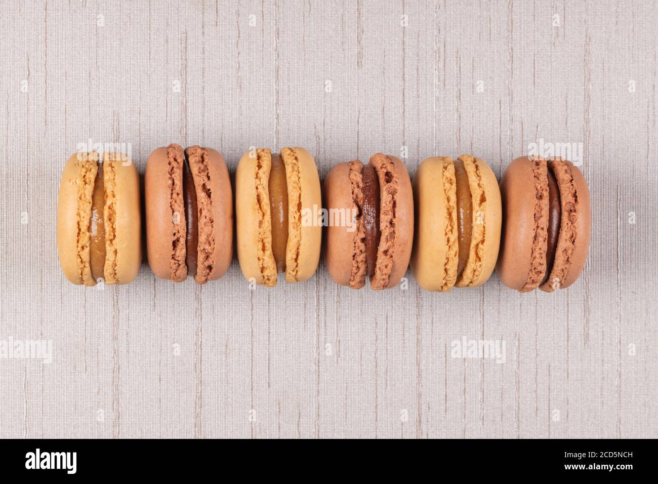 Six coffee and chocolated flavoured macaroons on beige vinyl background ...