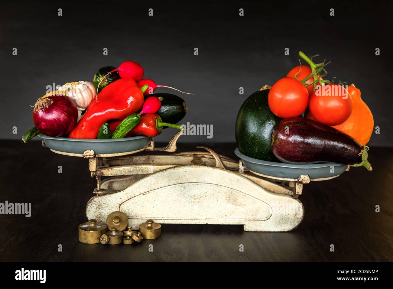 Fresh vegetables and old kitchen scale on a black background. Harvest ...