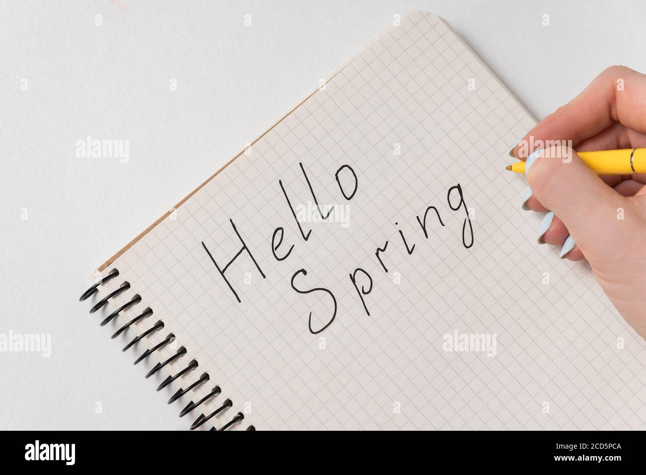 Hello spring motivation notice. Notepad and hand with pen on white ...