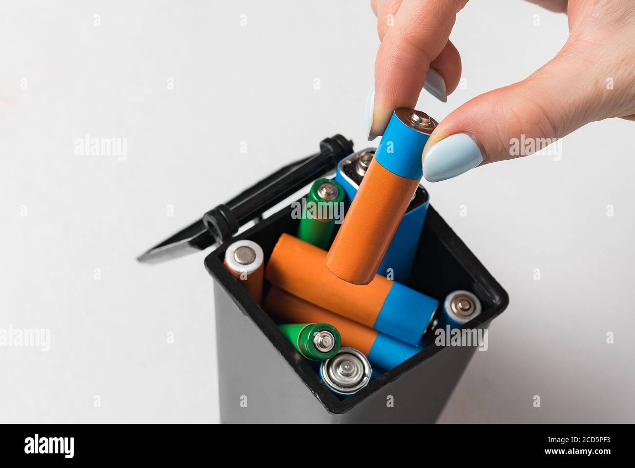 Female hand throws the used battery in the trash. Collection and ...