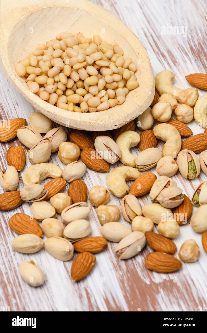 Close-up of peeled pine nuts in a wooden spoon on a wooden background ...