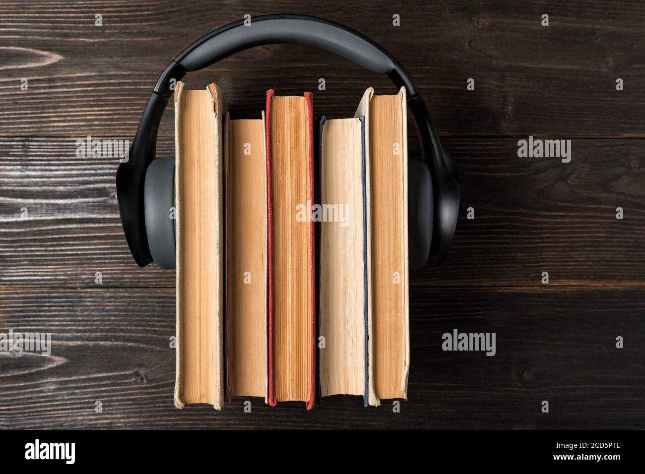 Headphones worn on a stack of old books on wooden background. Favorite ...