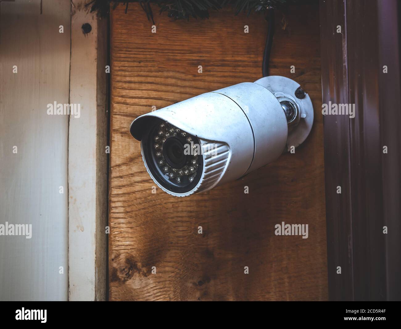 Cylindrical outdoor surveillance camera attached to a wooden surface ...
