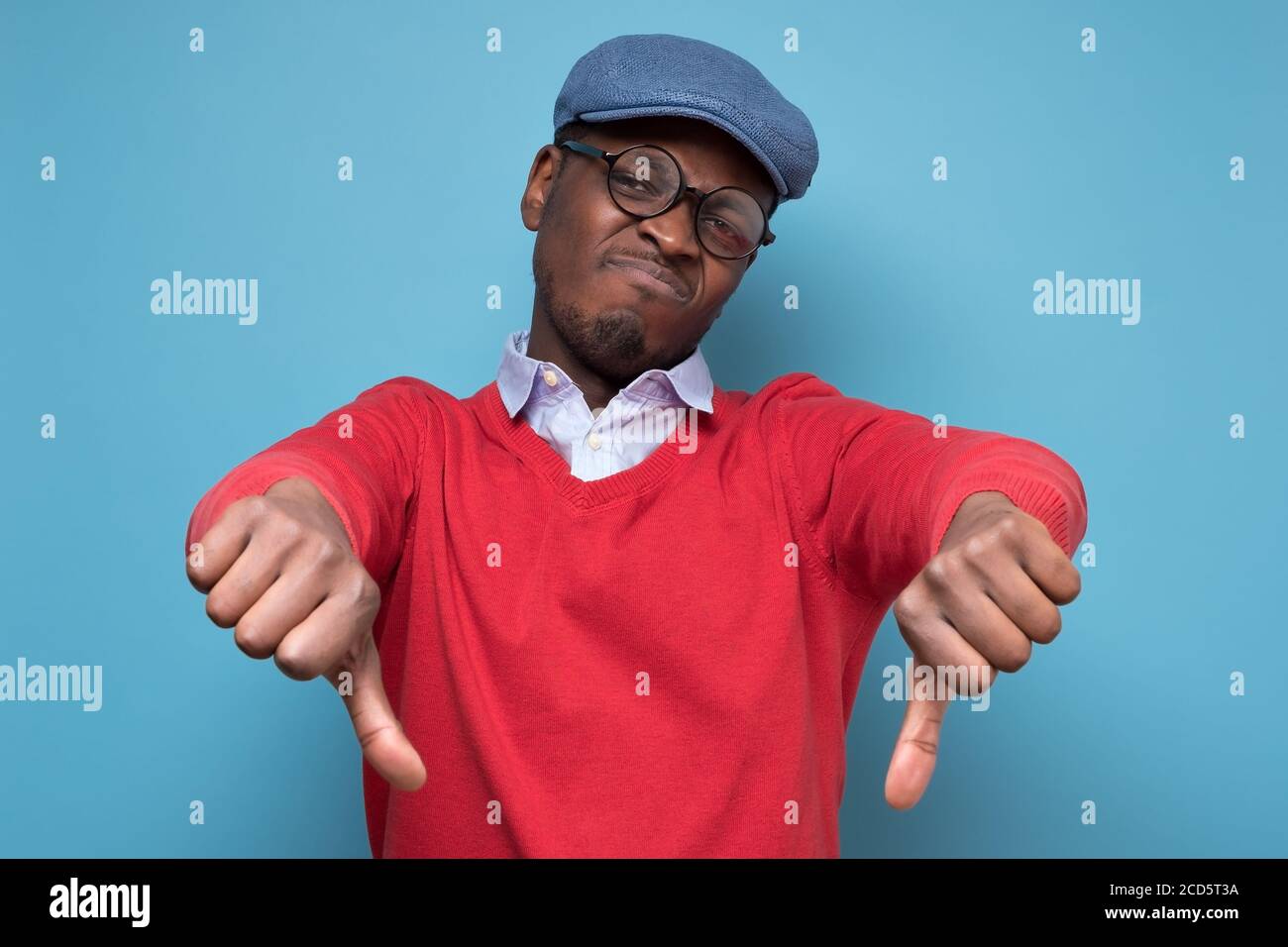 African man giving thumbs down gesture, looking with negative facial ...