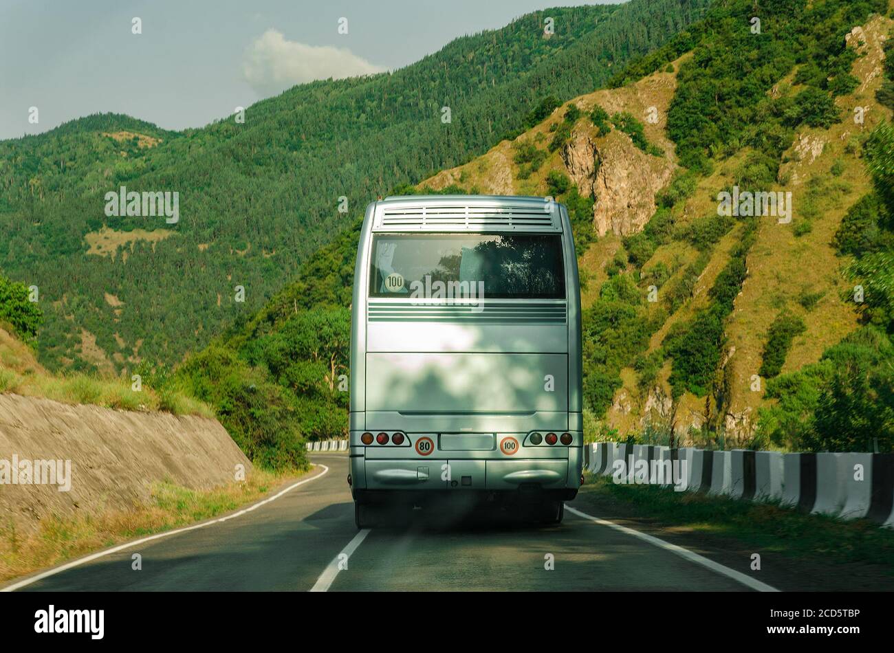 Rear side of a bus. Back view. Blank white bus on mountain highway ...