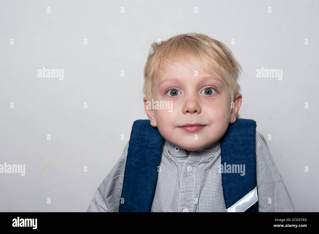 Cute fair-haired boy with surprised look on white background. Portrait ...