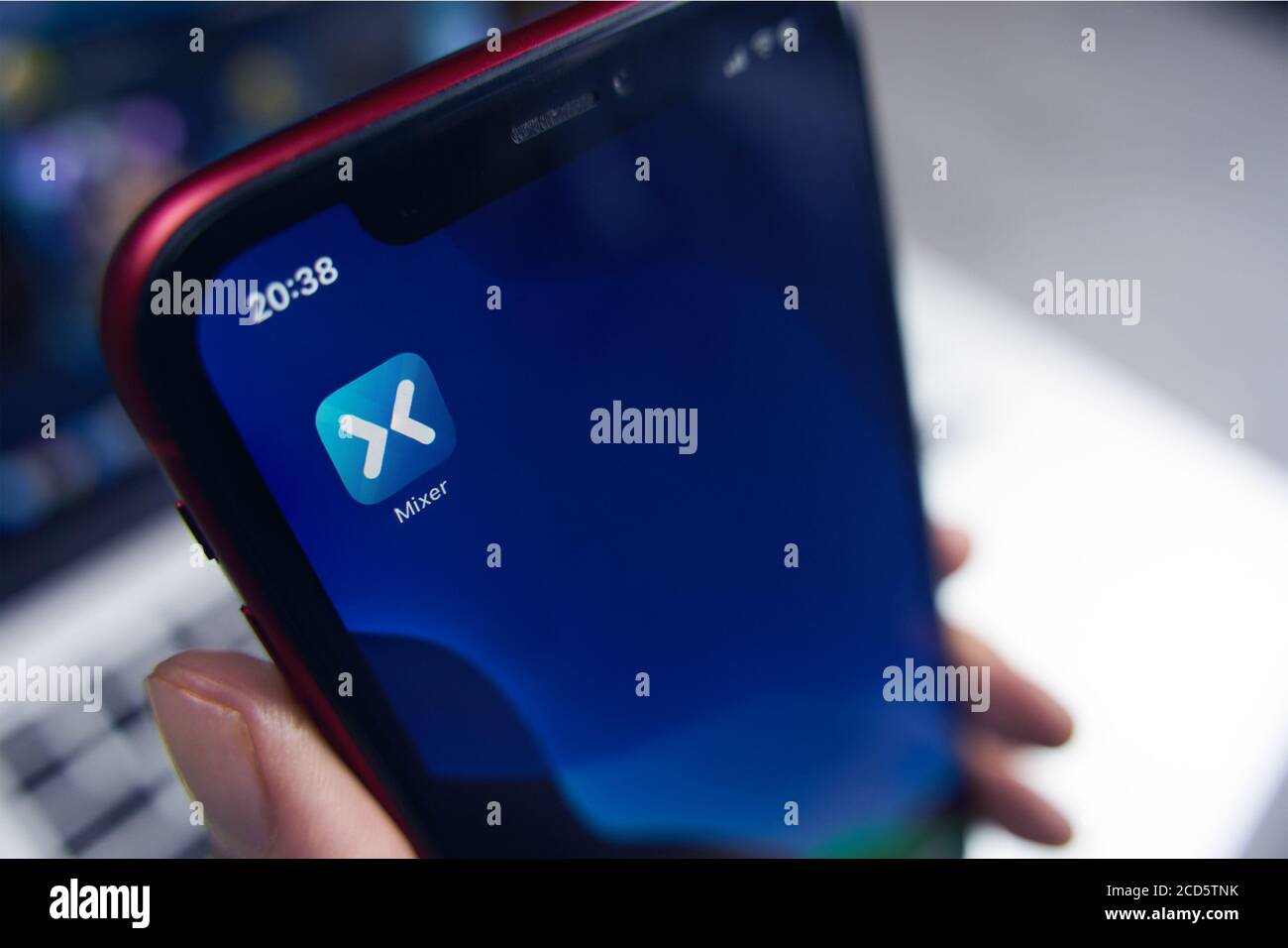Iphone in hand with Mixer streaming app icon on main screen of phone ...