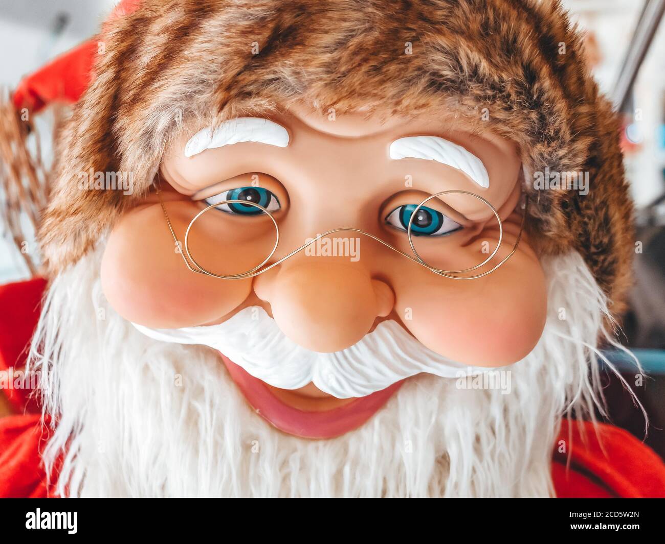 Toy smiling face of rubber santa claus with blue eyes and wire glasses ...