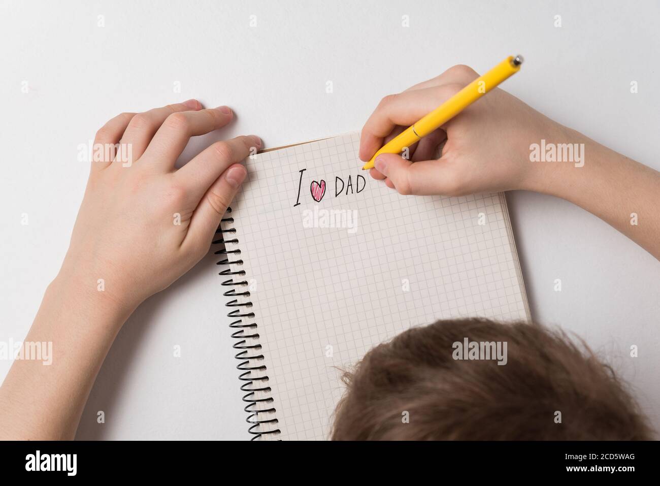 Child writes notice in notebook I love dad. White background Top view ...