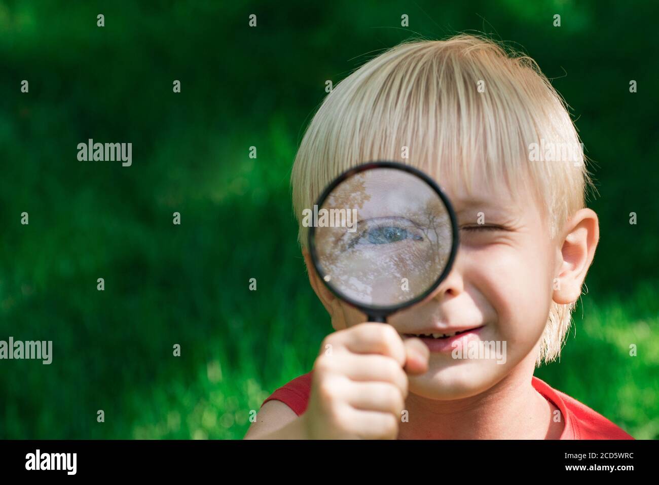 Cute curious child looking through a magnifying glass. Serious boy ...