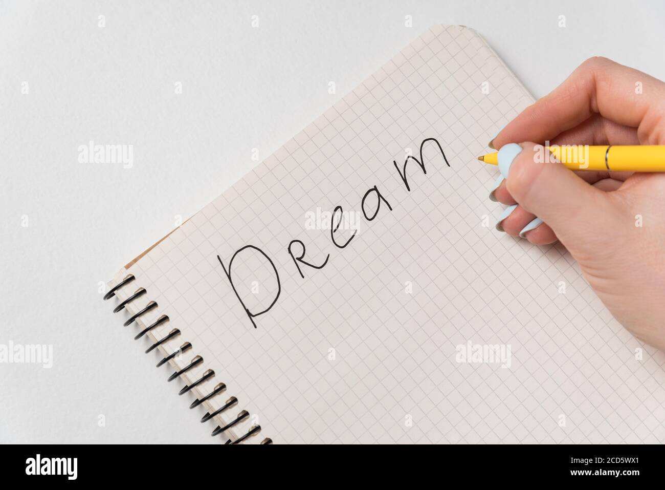 Word Dream written in the notebook. Female hand writing in notepad ...