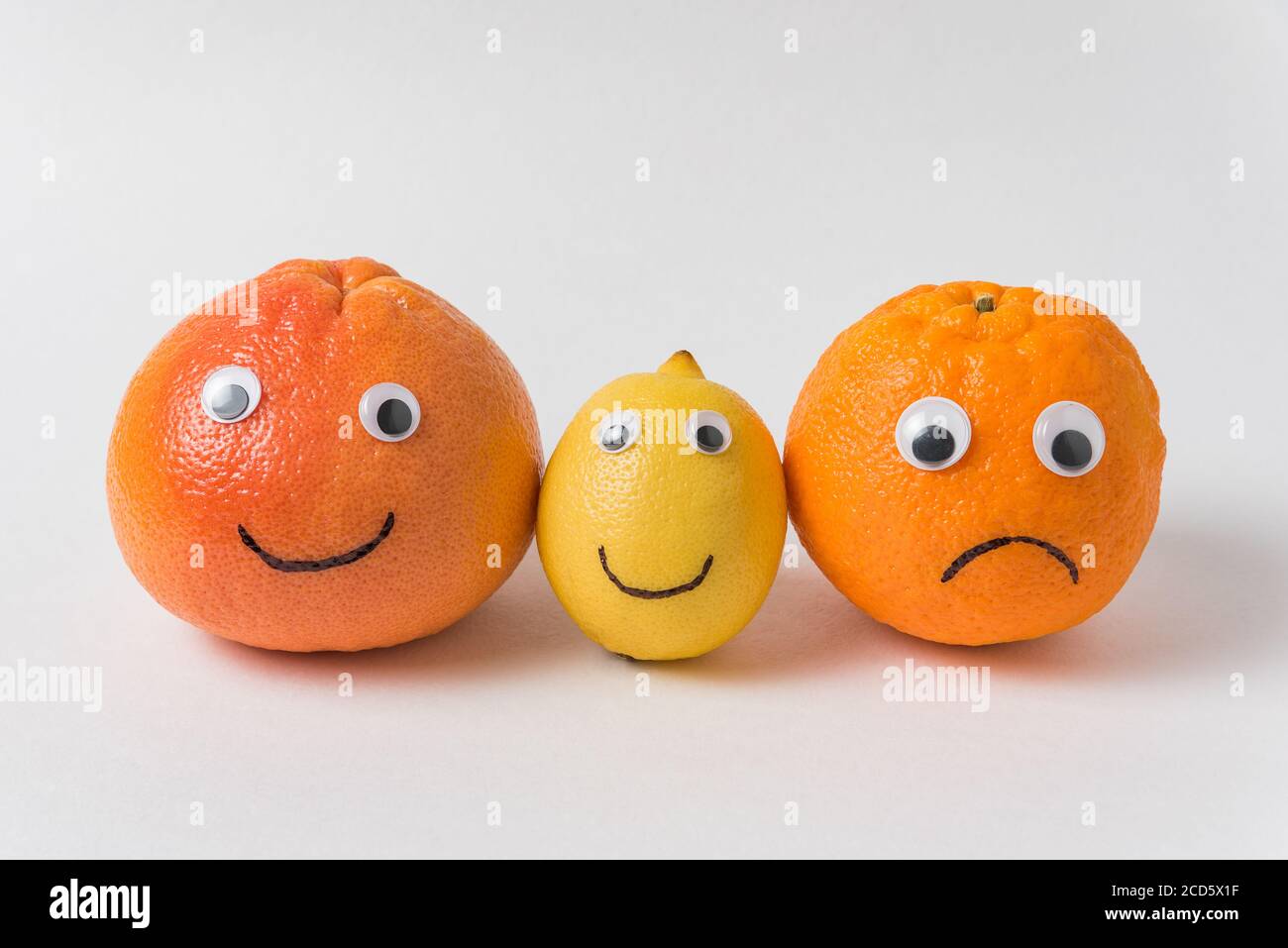 Grapefruit, lemon and orange with funny faces on white background ...