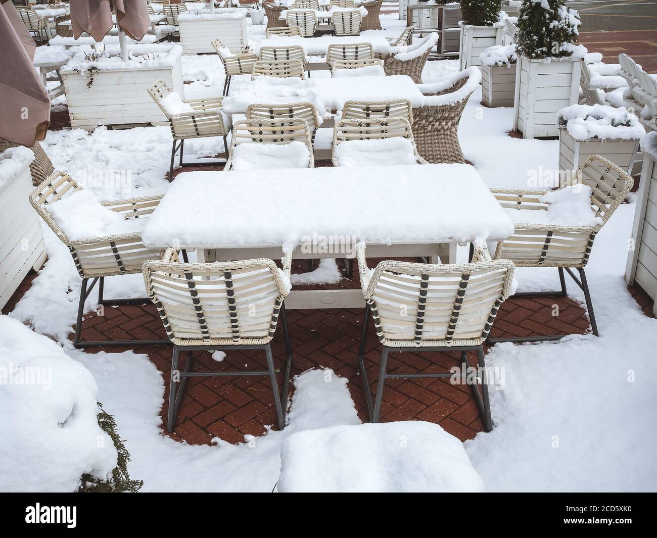 Street cafe with tables, chairs, umbrellas and wooden pots with bushes ...