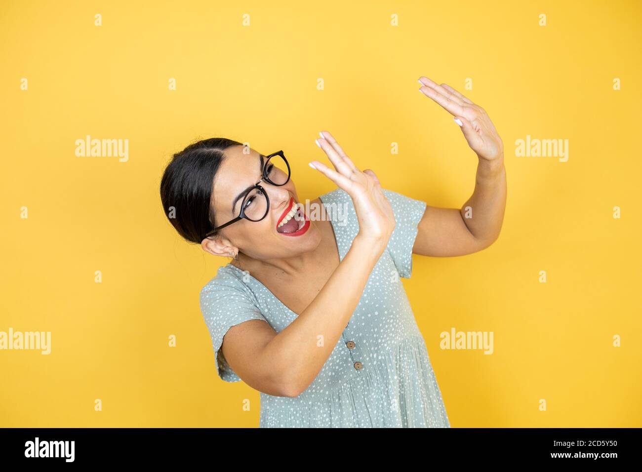 Young beautiful woman standing over yellow isolated background scared ...