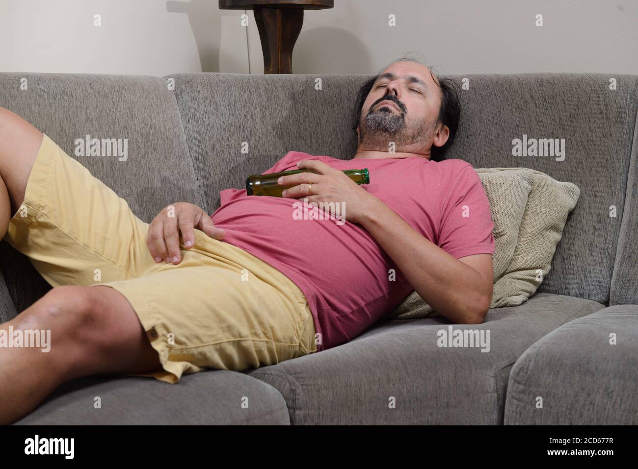 middle-aged man sleeping on the couch with beer bottle in hand Stock ...