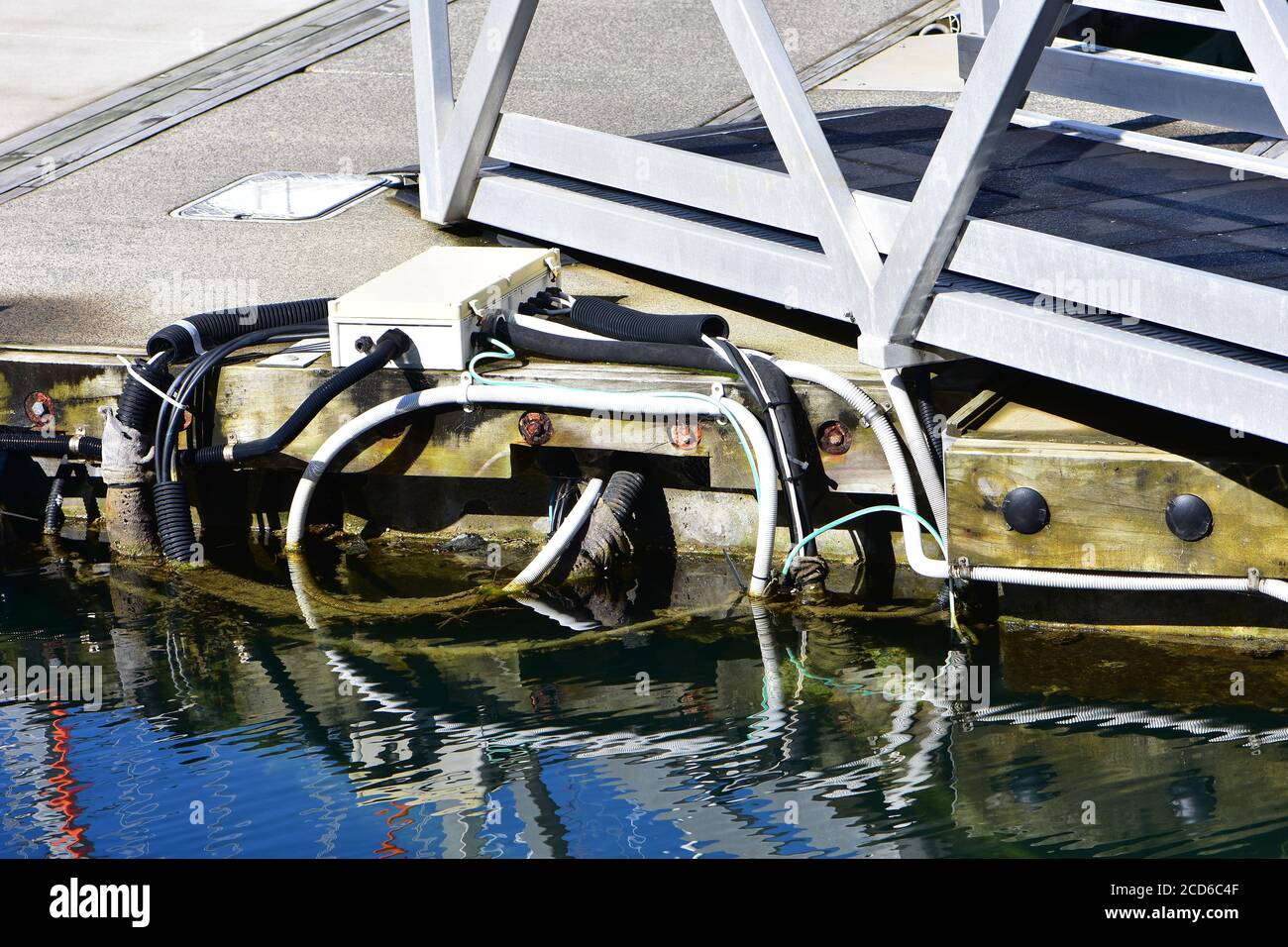 Insulated electric cables entering water from floating jetty in marina ...
