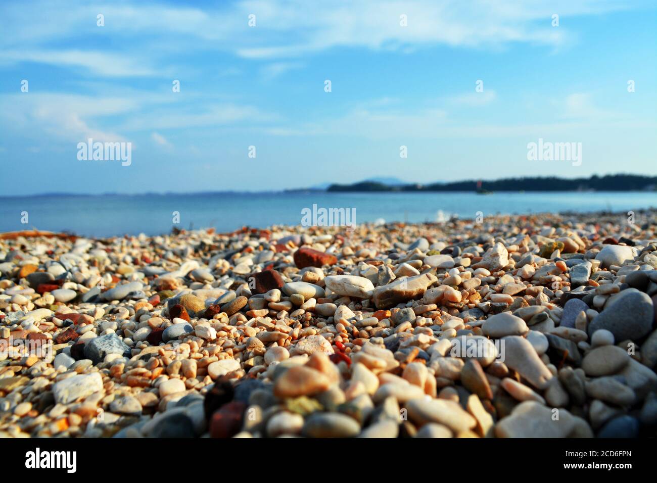 Closeup of small colorful stones on the shore surrounded by the sea ...