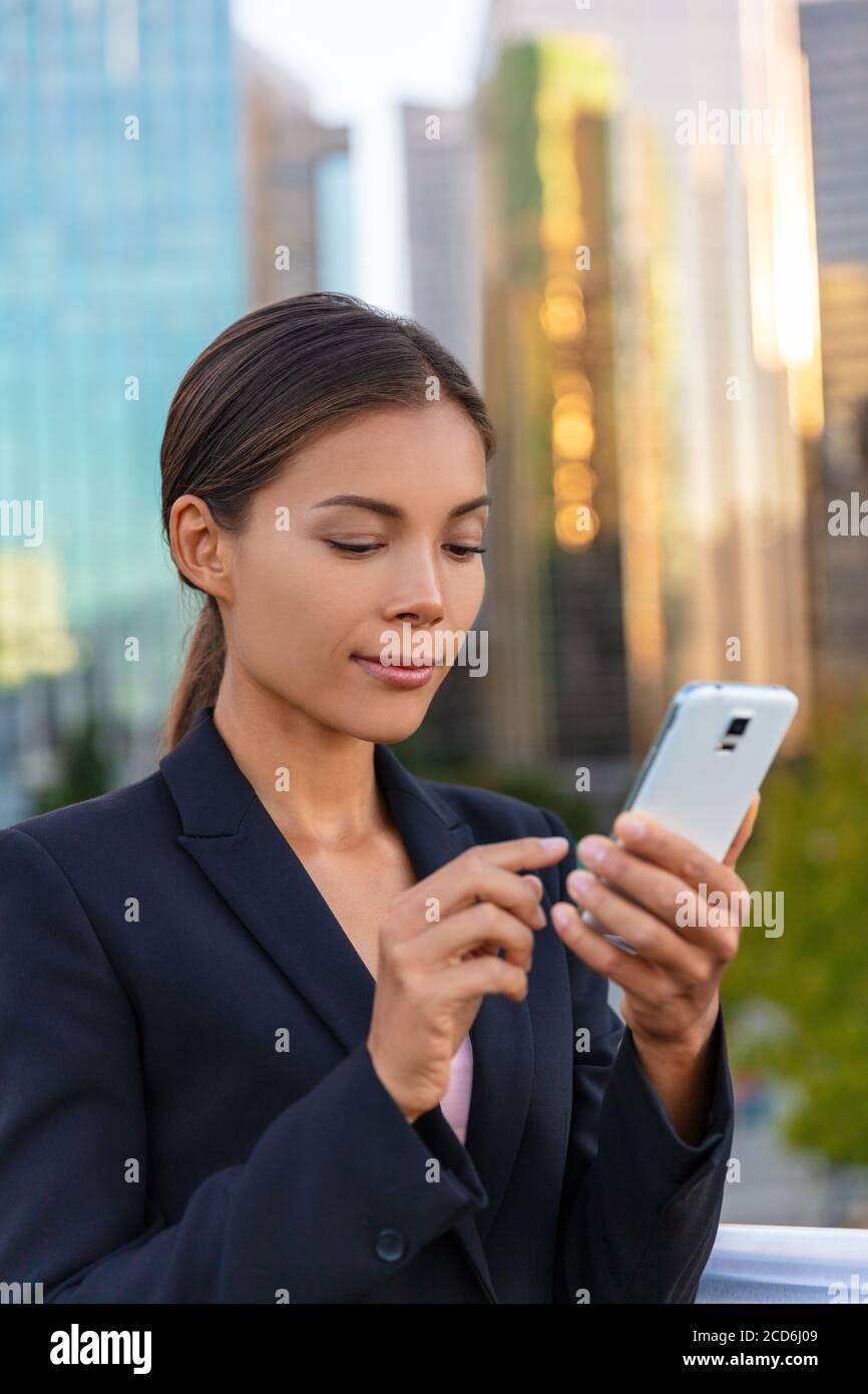 Asian business woman texting on mobile phone looking at online banking ...
