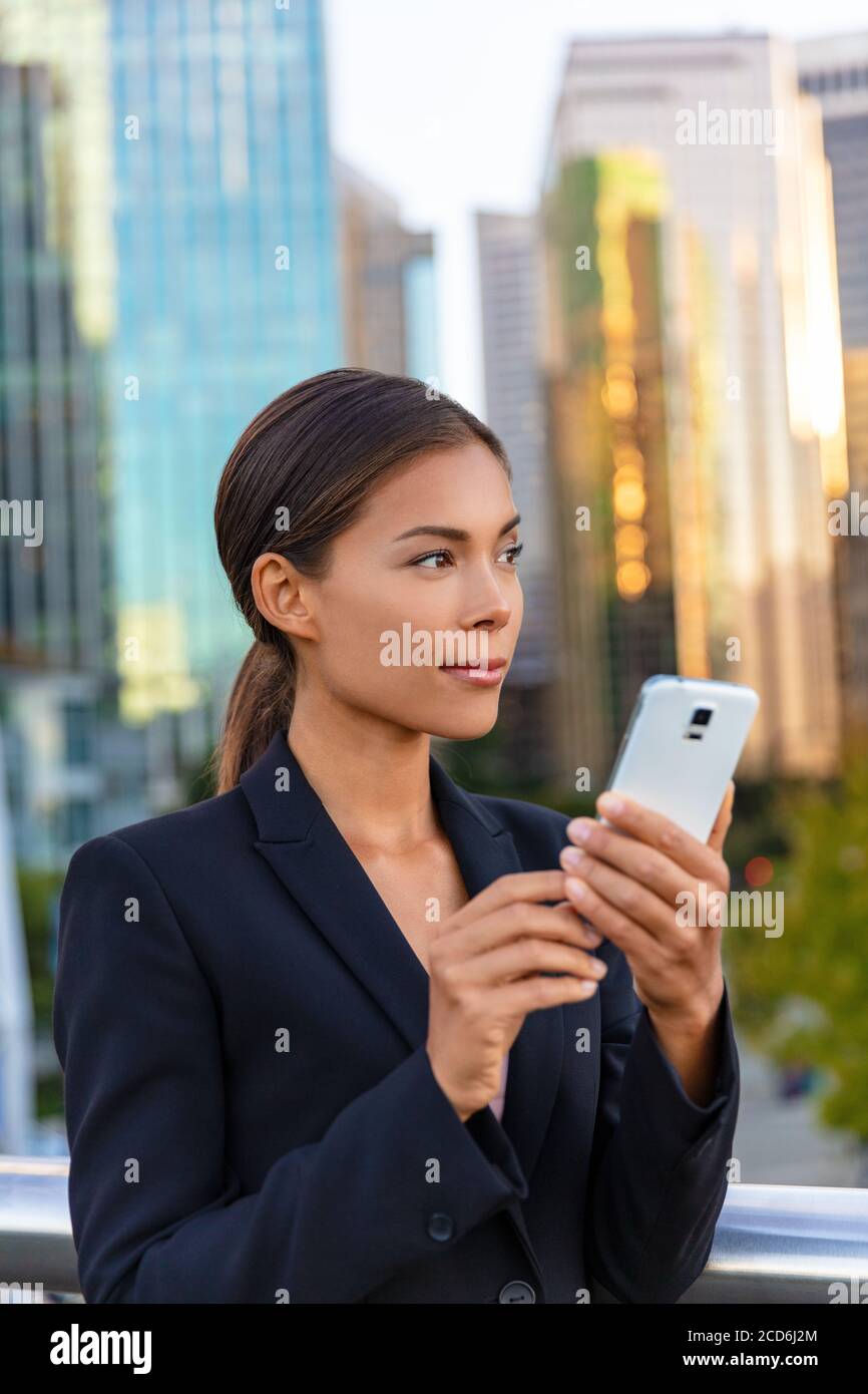 Asian business woman texting on mobile phone looking away to the side ...