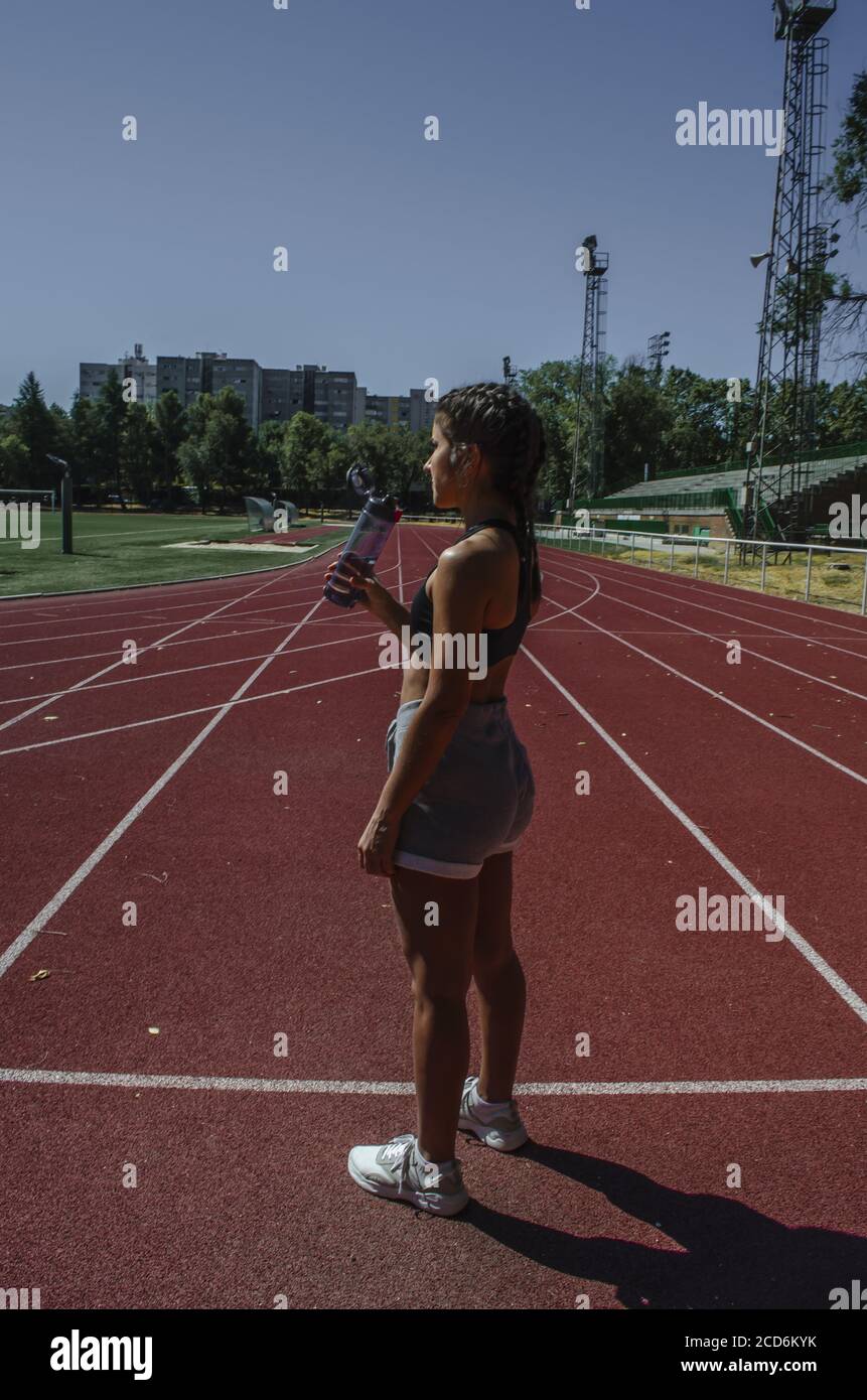 Vertical shot of a Hispanic young female drinking water while working ...